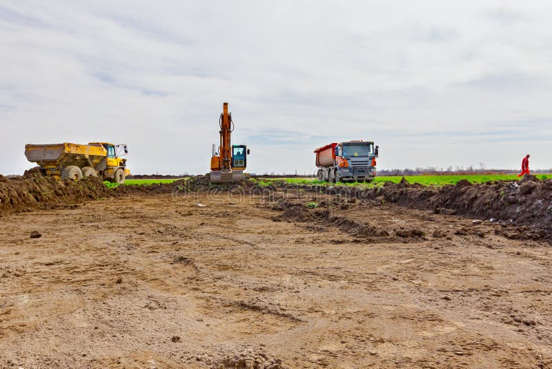 Big Excavator is Loading Two Trucks with Ground on Building Site Stock ...