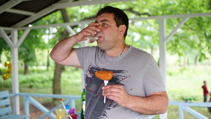 Big Man Drinking and Eating a Cutlet in a Park Pavilion Stock Image ...