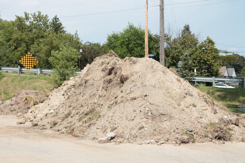 Big Pile of Dirt on Road with Bottom of Bridge and Trees Behind. P ...