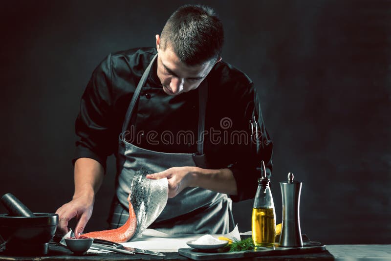 The Big Salmon is in the Hands of the Chef Cook. he is Using a Knife To ...