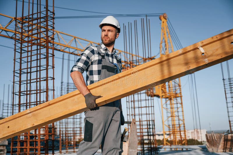 With Big Wooden Plank in Hand. Man is Working on the Construction Site ...