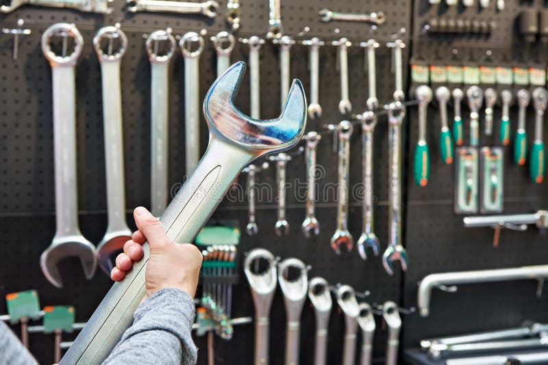 Big Wrench in Hand Near Wall with Tools in Store Stock Photo - Image of ...