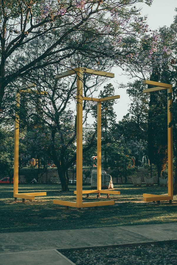 Big Yellow Metal Poles Forming a Square Surrounded by Trees in a Park ...
