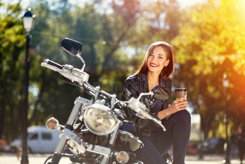 Biker Girl in a Leather Jacket on a Motorcycle Drinking Coffee Stock ...
