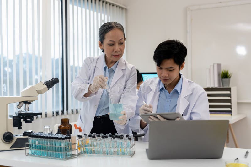 Biochemical Research Scientist Team Working with Microscope for Vaccine ...