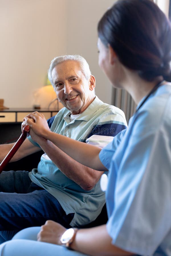 Biracial Female Physiotherapist Consoling Caucasian Senior Man Holding Walking Cane At Home
