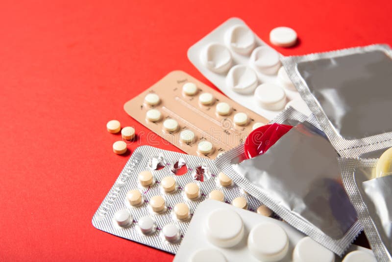 Birth Control Pills and Condoms on a Red Background. Close-up Stock ... Birth Control Pills and Condoms on a Red Background. Close-up Stock ...