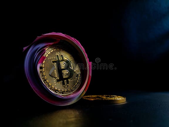 Bitcoin Token Rests Against a Rolled Stack of Banknotes on a Dark ...