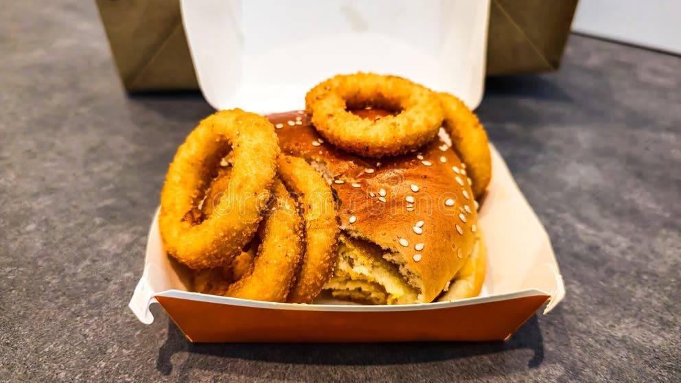 A Bitten Hamburger and Fried Onion Rings in a Box on the Floor Stock ...