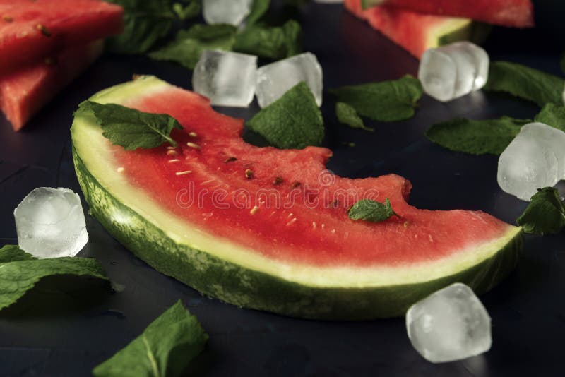 Bitten Slice of Watermelon with Mint Leaves and Ice Cubes on Black ...