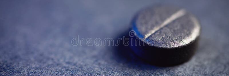 The Black Activated Charcoal Tablet. on a Dark Background. There`s Blue ...