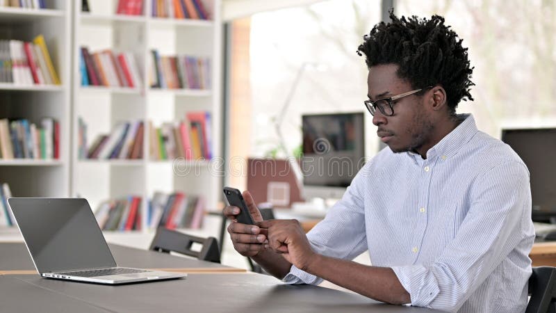 African Man Browsing Internet on Smartphone at Work Stock Image - Image ...