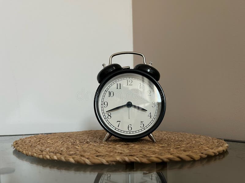 A Black Alarm Clock with a White Face Sits on a Brown Mat Stock Photo ...
