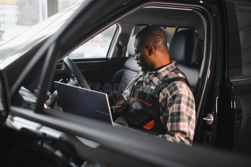 Black Auto Mechanic Running Diagnostic on Laptop while Analyzing Engine ...
