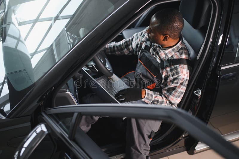 Black Auto Mechanic Running Diagnostic on Laptop while Analyzing Engine ...