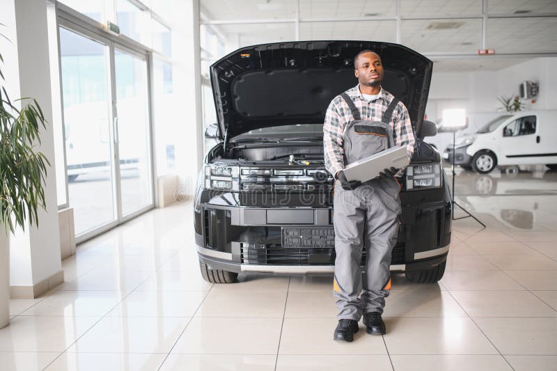 Black Auto Mechanic Running Diagnostic on Laptop while Analyzing Engine ...