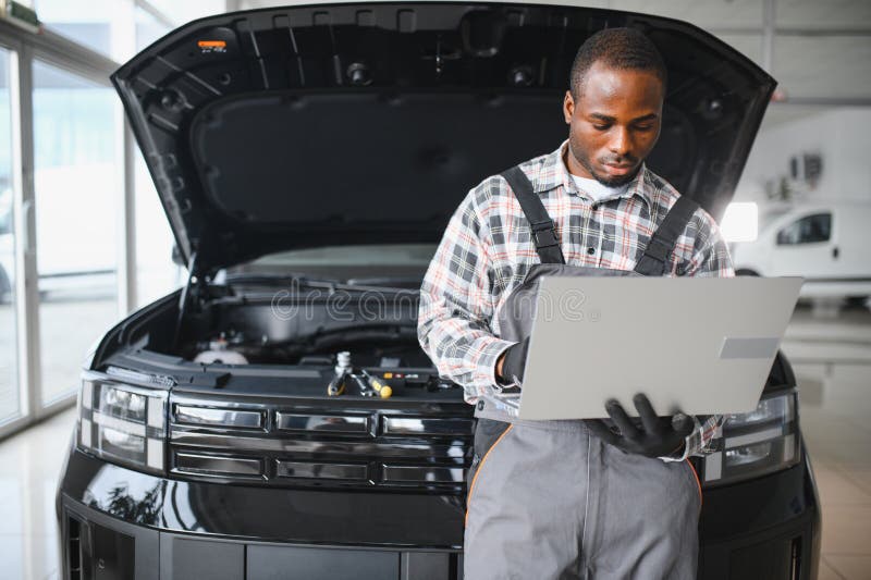 Black Auto Mechanic Running Diagnostic on Laptop while Analyzing Engine ...
