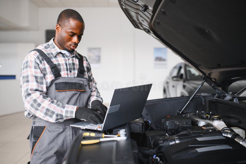 Black Auto Mechanic Running Diagnostic on Laptop while Analyzing Engine ...