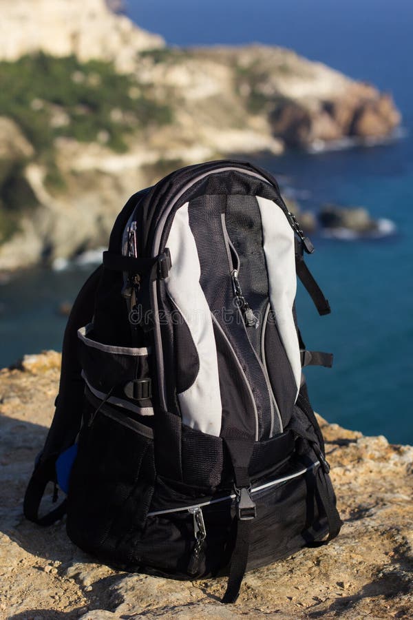 Black Backpack on the Rock Peak Over Sea Background Stock Photo - Image ...