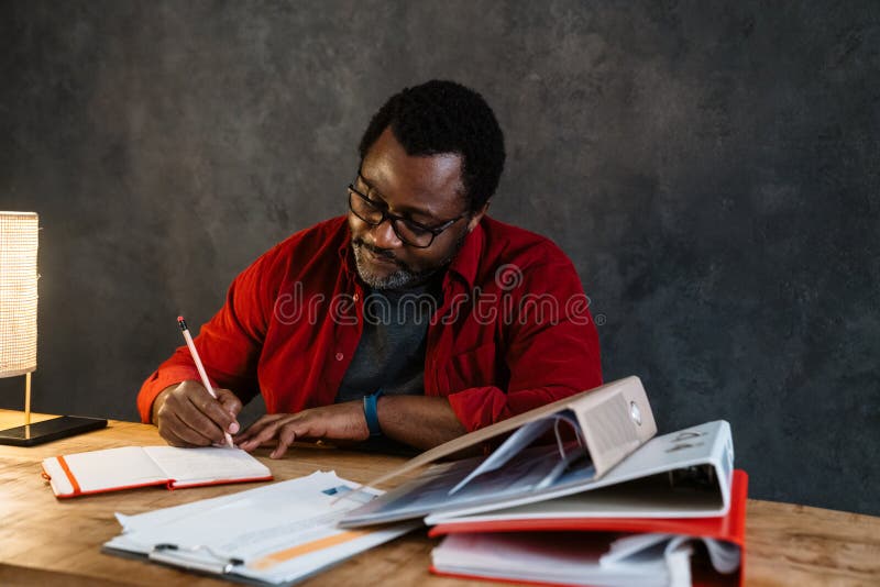 Black Man Writing Down Notes while Leaning on Concrete Wall Stock Image ...