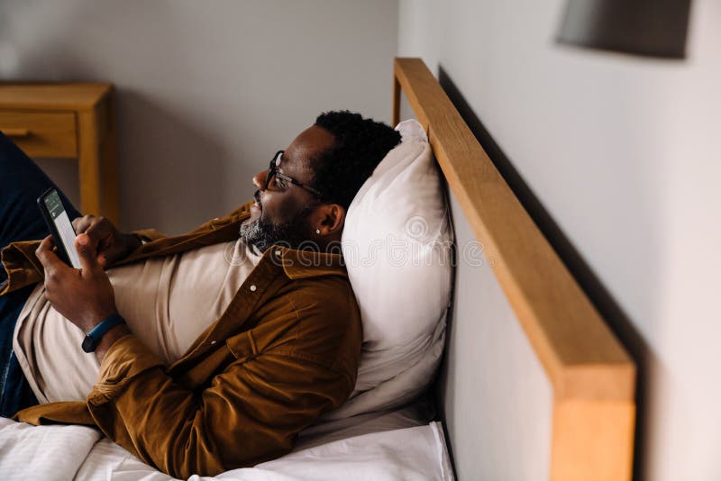 Black Bearded Man Using Cellphone while Resting in Bed Stock Image ...