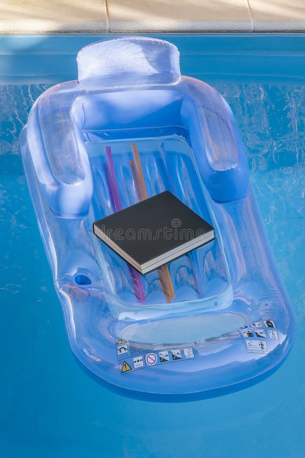 A Black Book Rests on an Inflatable Pool Mat Floating on the Water ...
