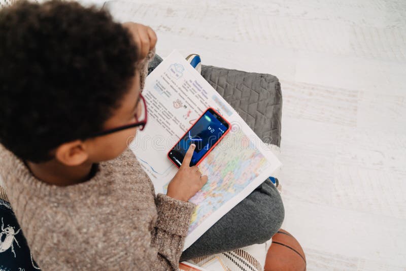 Black Boy Using Mobile Phone and Doing Homework on Sofa Stock Image ...