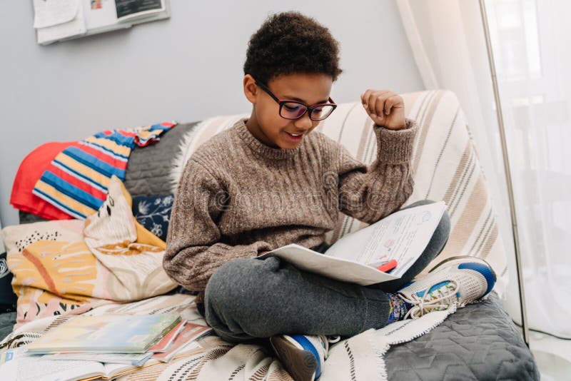 Black Boy Using Mobile Phone and Doing Homework on Sofa Stock Photo ...