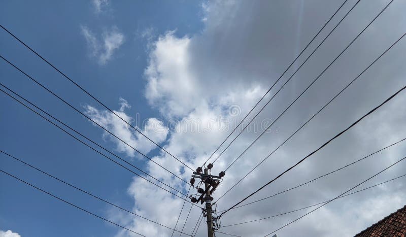 Black Cables on Electric Poles Stretched Against the Blue and Cloudy ...