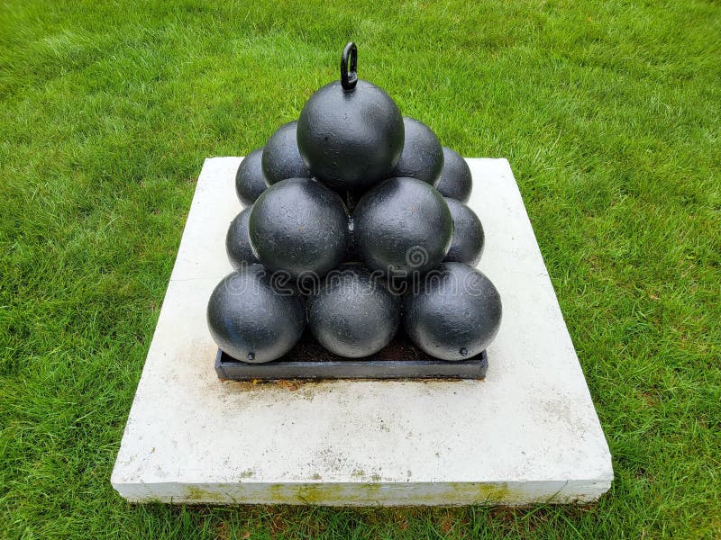 Black Cannonballs in Pyramid Stack on Cement on Grass Stock Photo ...