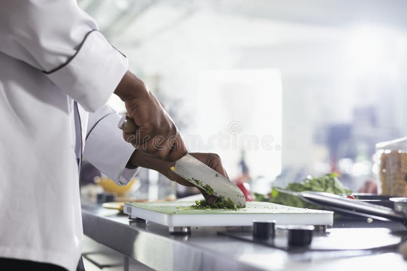 Black Chef Mincing Herbs and Other Greenery in the Restaurant Kitchen ...