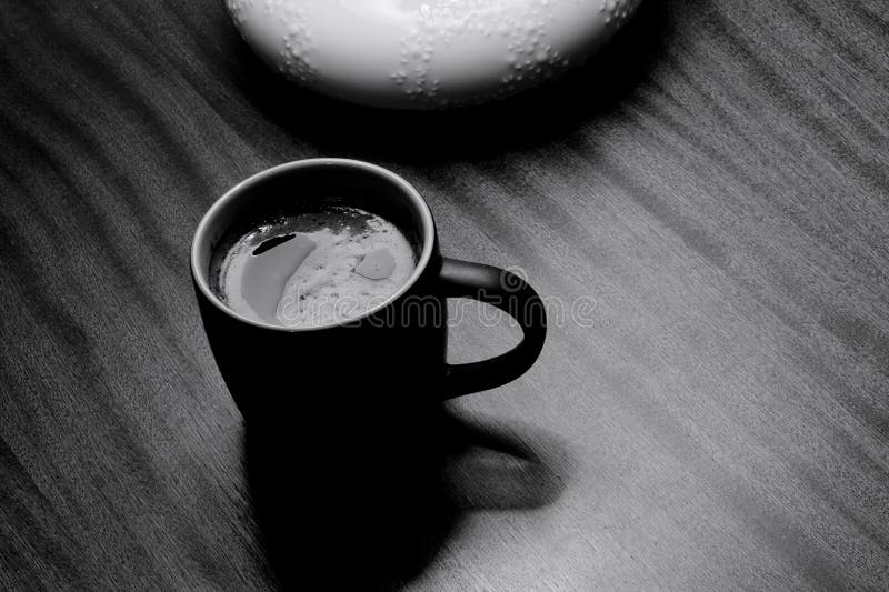 Black Mug of Coffee on Table Under Lamp, Monochrome Stock Image - Image ...
