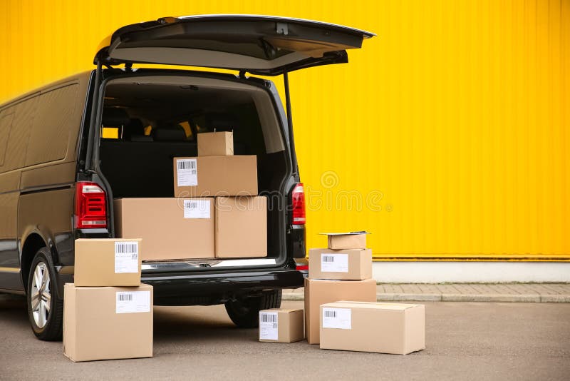 Black Delivery Van and Many Different Parcels Near Yellow Wall Outdoors ...