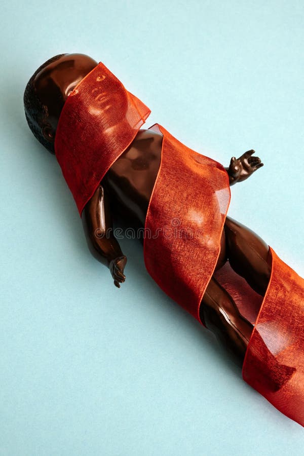 Black Doll Covered with Red Ribbon Lying on Blue Background Stock Image ...