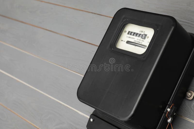Black Electric Meter on Grey Wooden Wall, Space for Text. Measuring ...