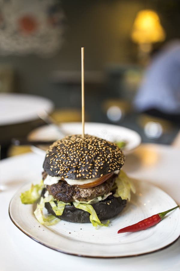 Black Flour Burger on a Plate with Red Hot Peppers Stock Photo - Image ...