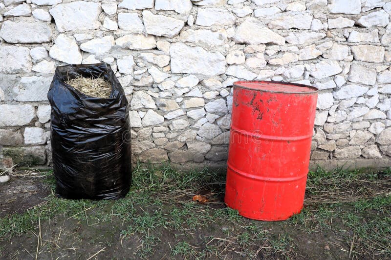 The Waste Disposal Setup Includes a Black Bag and a Red Barrel Placed ...