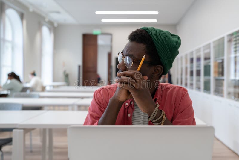 African Student Guy Distracted from Study, Sitting at Table with Laptop ...