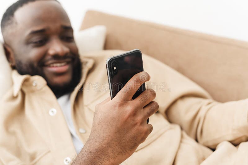 Black Guy Using Smartphone, Browsing Internet and Texting while Lying ...