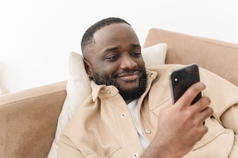 Black Guy Using Smartphone, Browsing Internet and Texting while Lying ...
