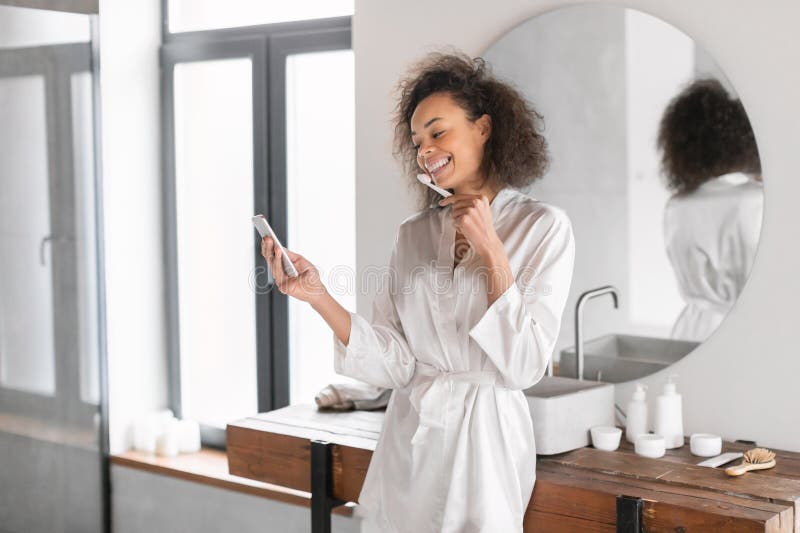 Black Lady Getting Ready Brushing Teeth Using Phone in Bathroom Stock ...