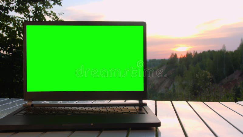 Black Laptop with a Green Screen is on a Folding Table at Sunset at Top ...