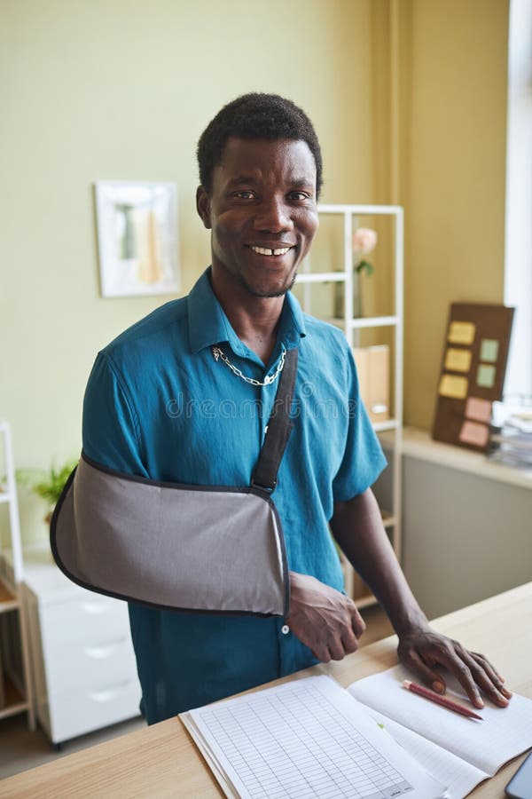Black Man with Arm Sling Working at Standing Desk Smiling at Camera ...