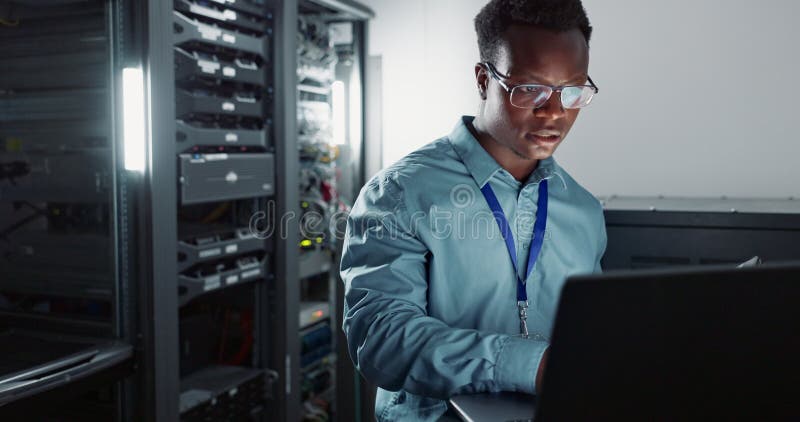 Black Man Engineer And Laptop In Server Room For Database Update Cyber Security Or Coding