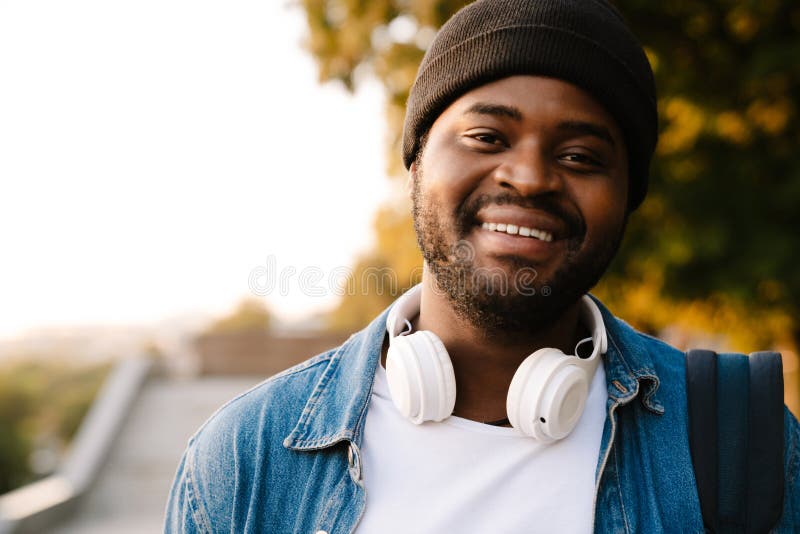 Black Man with Headphones Smiling while Walking in Park Stock Photo ...