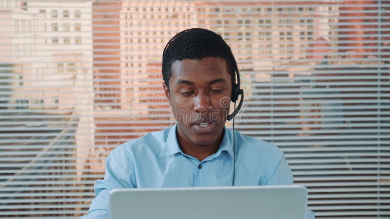 Black Man in Headset Speaking with Somebody and Working on the Computer ...