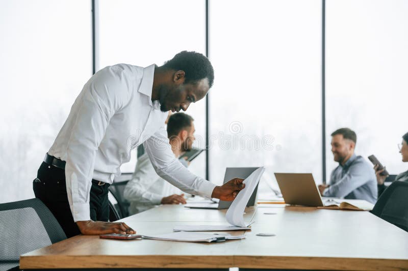 Black Man is Reading the Document that is on Table. Team of Office ...