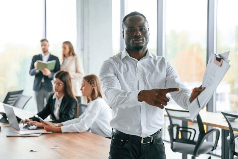 Black Man is Standing and Holding Documents. Group of Office Workers are Together Indoors Stock ...