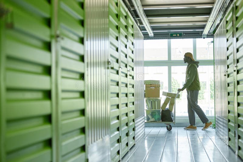 Black Man Transporting Boxes on Cart into Self Storage Unit at ...