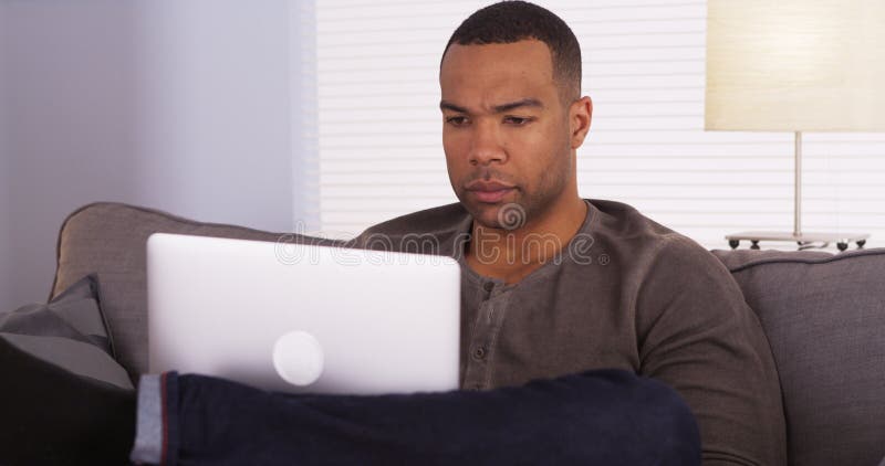 Black Man Using Laptop on Couch Stock Image - Image of indoors, sitting ...